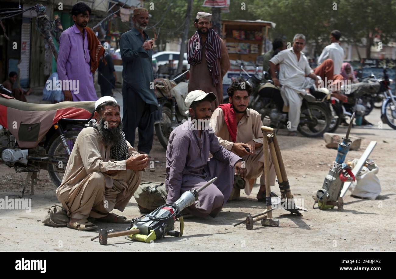 Pakistani day laborers sit next to their tools as they wait for work on ...