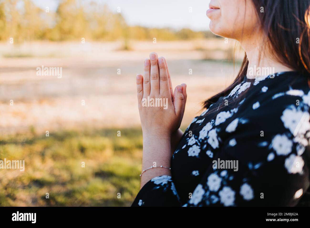 Unrecognizable believer person with praying hands at sunset in the ...
