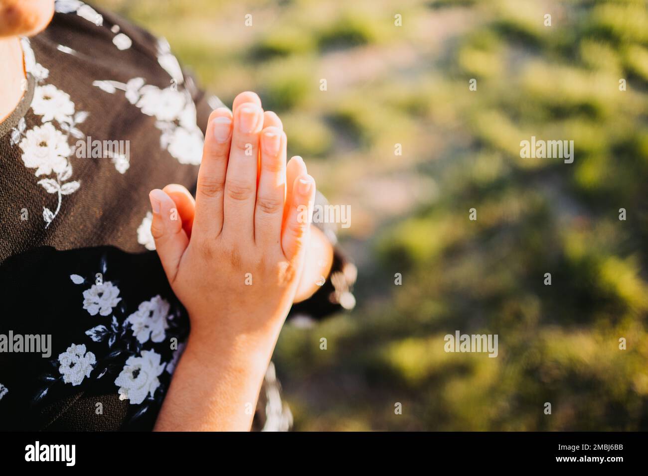 Unrecognizable believer person with praying hands at sunset in the ...