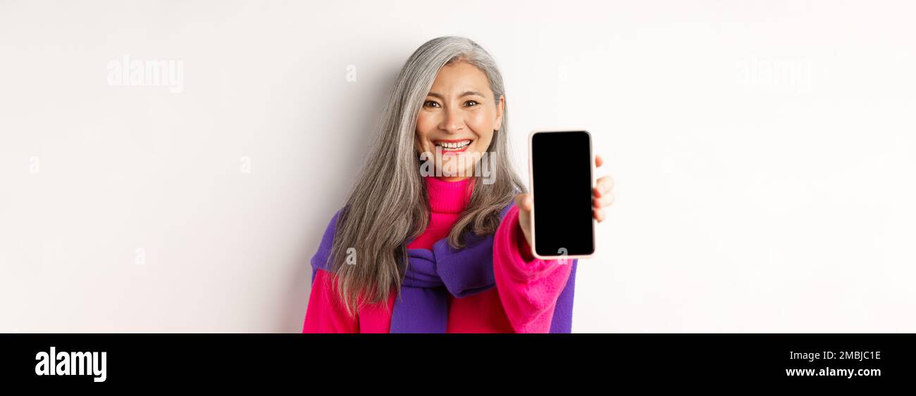 Online shopping. Close up of modern asian senior woman extending hand ...