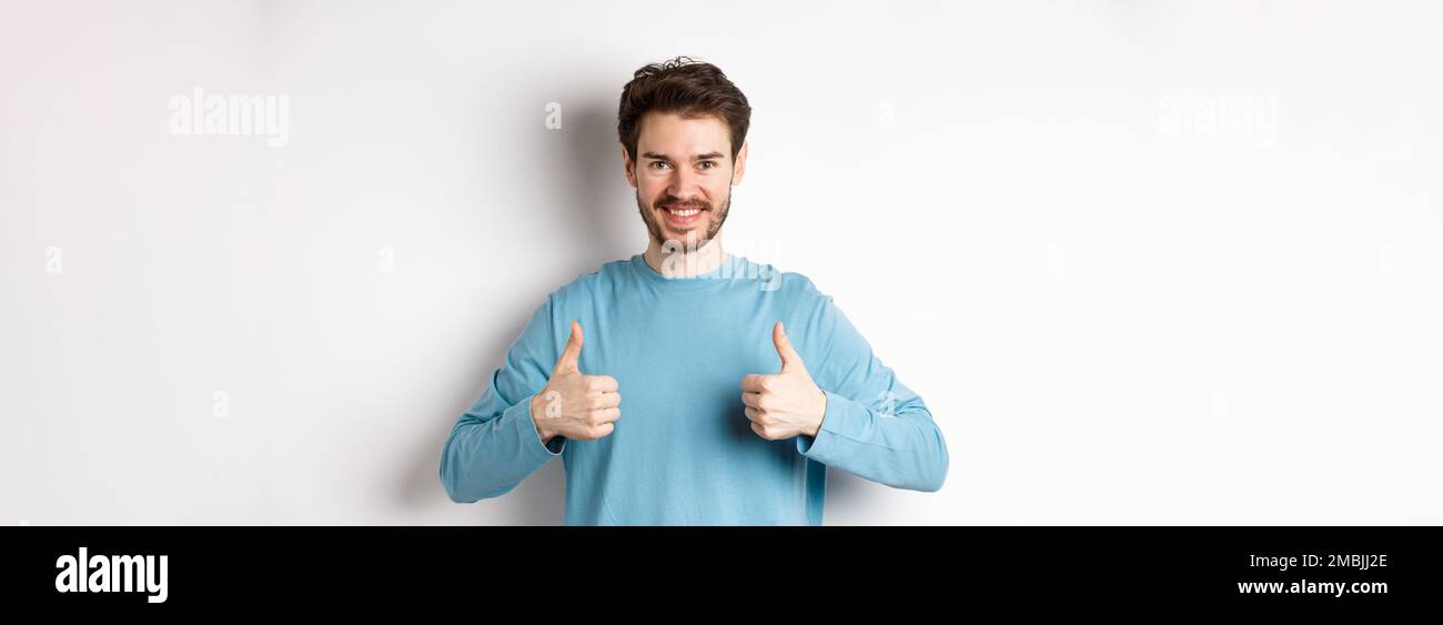 Smiling handsome man showing thumbs up, like and approve good choice ...