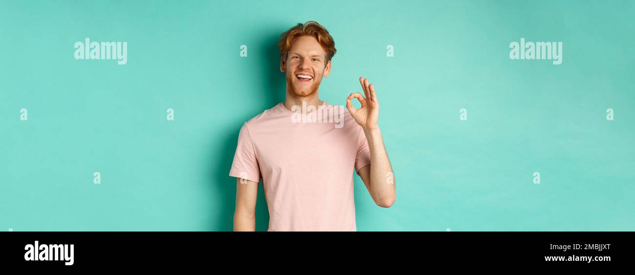 Handsome young bearded man in t-shirt showing Ok sign, smiling with ...