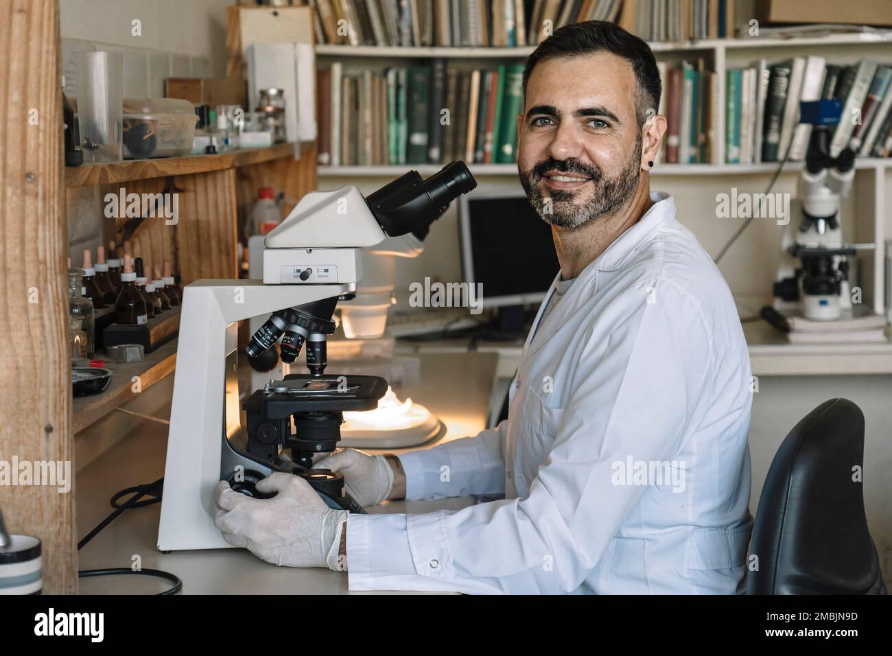 Scientist in front of microscope, smiling and looking at camera Stock ...