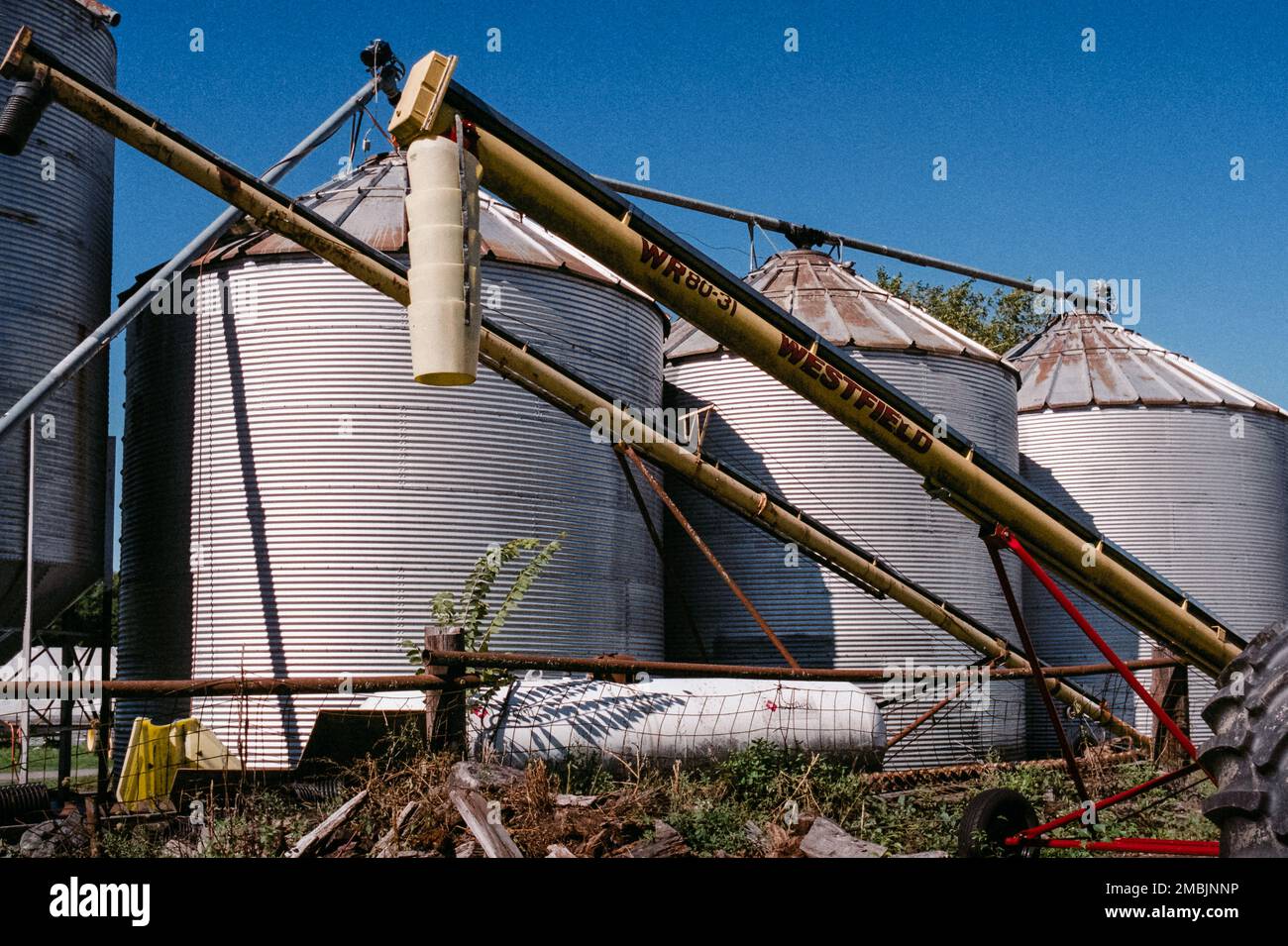 A grain auger stands in front of a metal silo at Spring Brook Farm in ...
