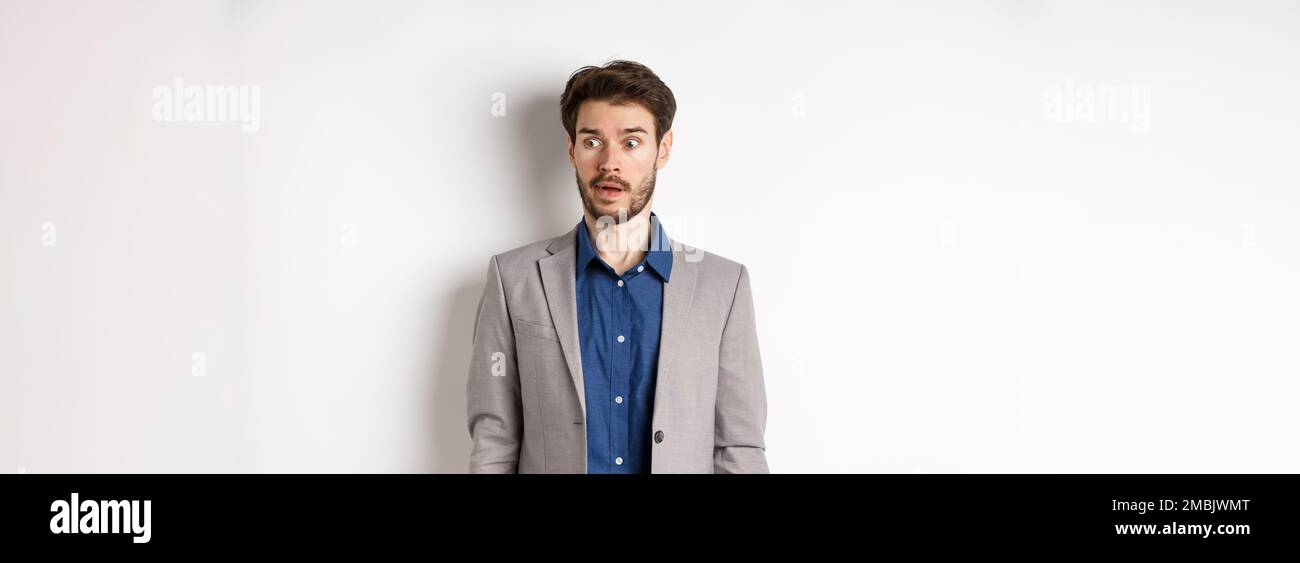 Shocked male entrepreneur in suit looking aside at logo with startled ...