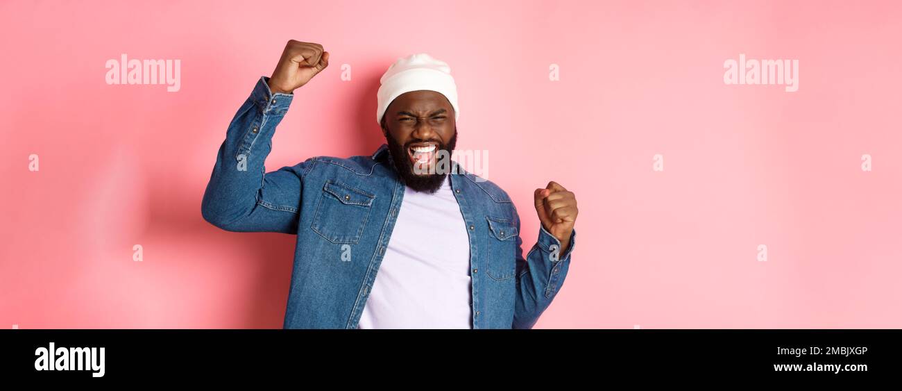 Lucky african-american guy winning prize, raising hands up in triumph ...