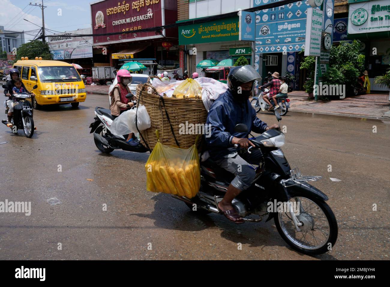 A vendor transports loaves of bread on his motorcycle during the rainy ...
