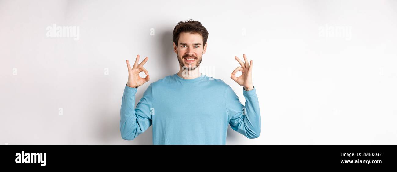 Very good. Smiling handsome guy showing okay signs and looking ...