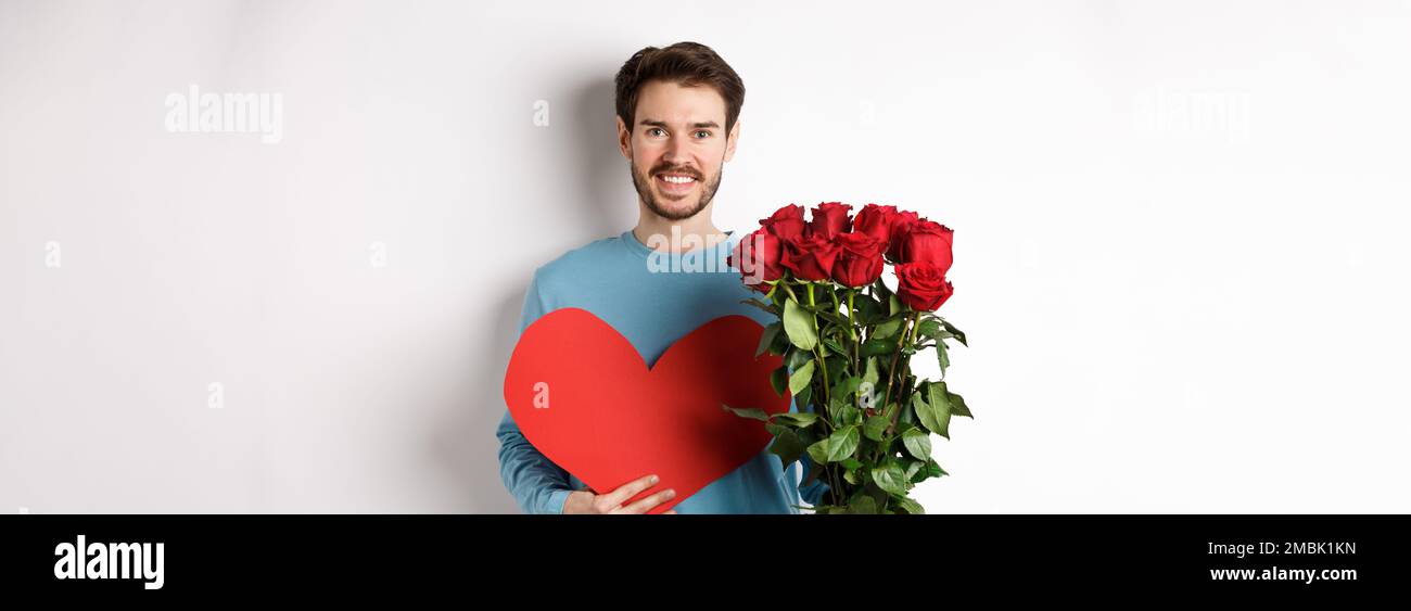 Romantic people. Handsome smiling man holding bouquet of roses and big ...