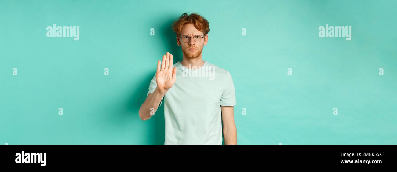 Angry and serious young man with red hair, wearing glasses, showing ...