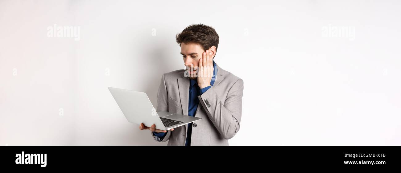 Shocked and worried businessman making mistake on laptop, looking at ...