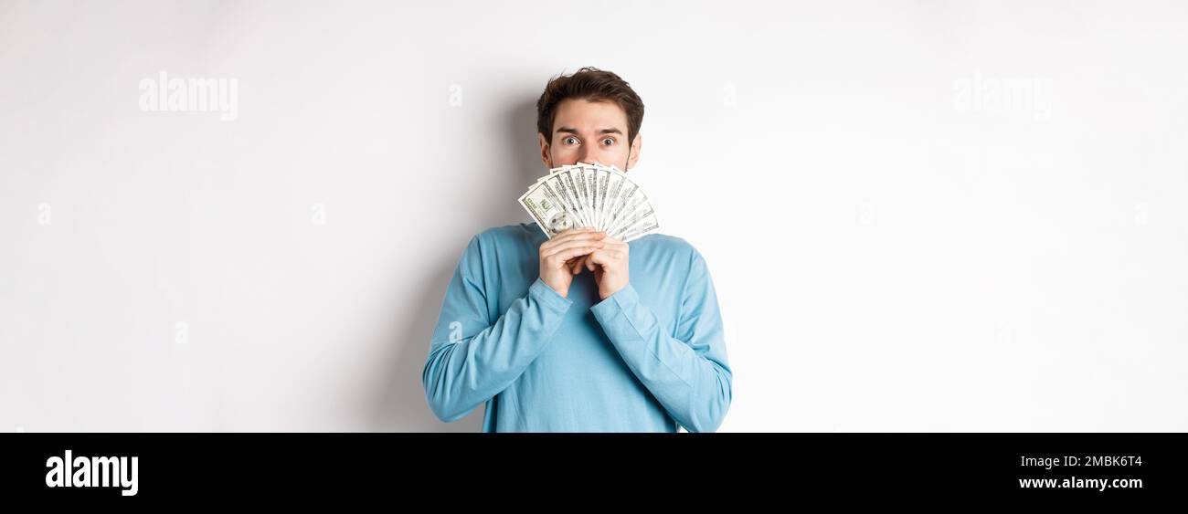 Surprised and amazed handsome guy showing money, looking at promo offer ...