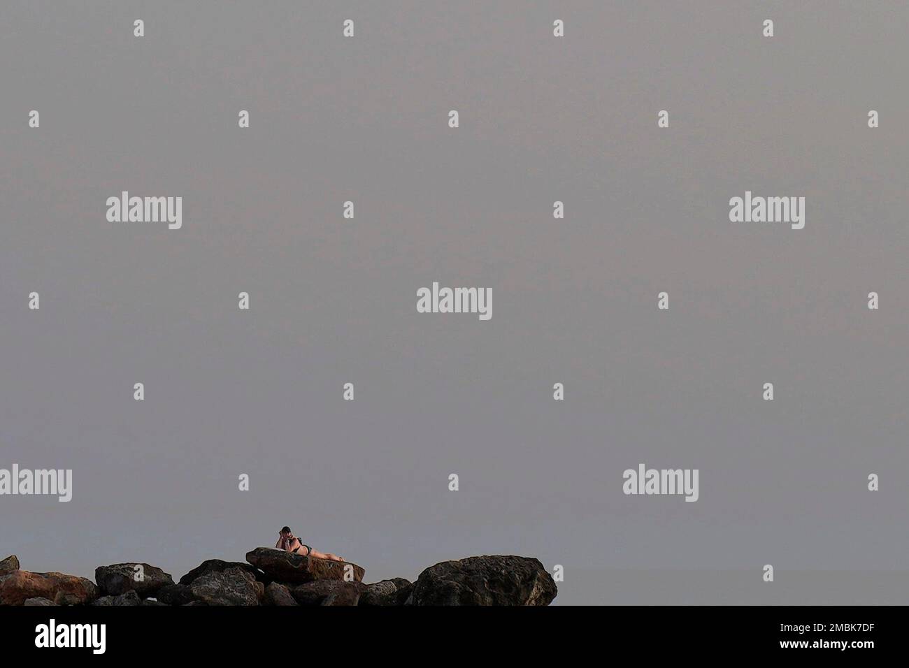 A woman watches the sea in a haze caused by a dust storm in the ...