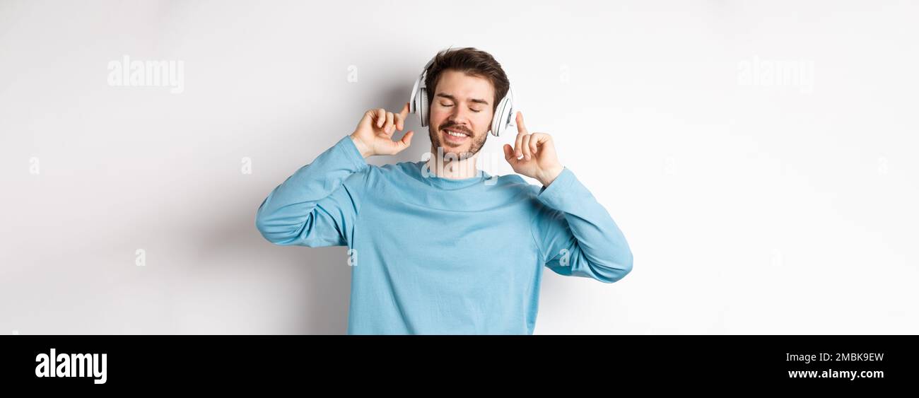 Handsome man listening music in wireless headphones and smiling ...