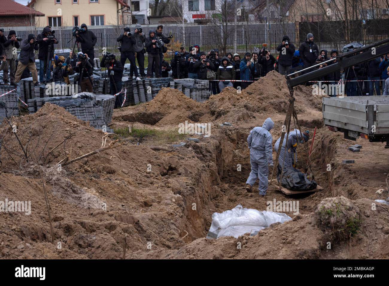 FILE - Cemetery workers exhume the corpse of a civilian killed in Bucha ...