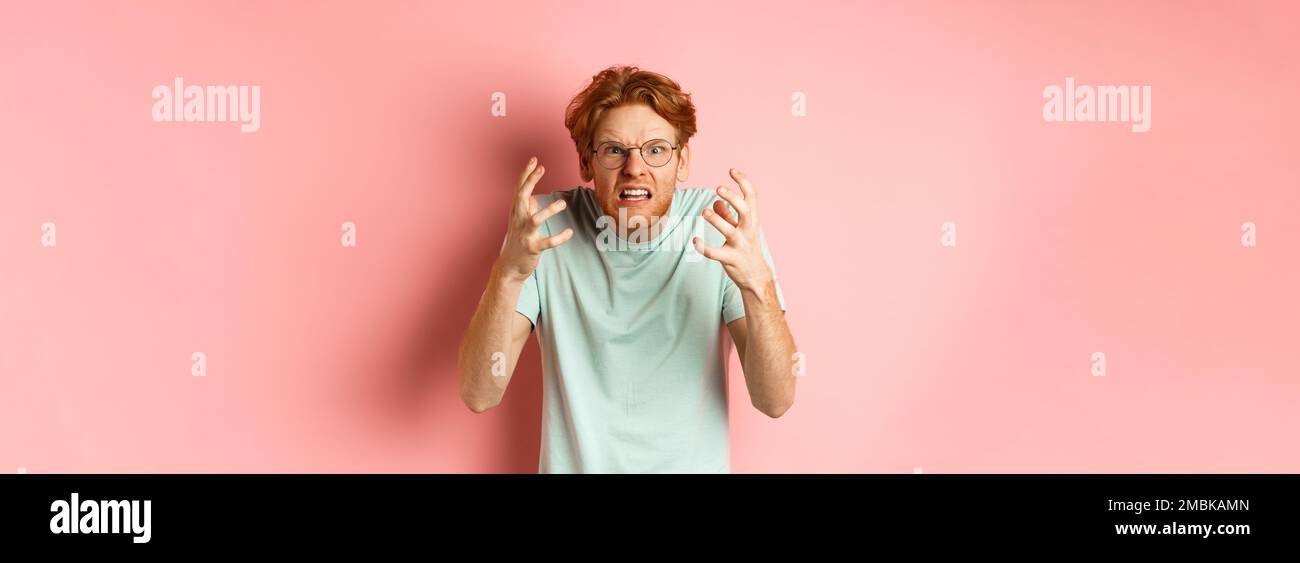 Angry redhead guy in glasses shouting, frowning and shaking hands with ...
