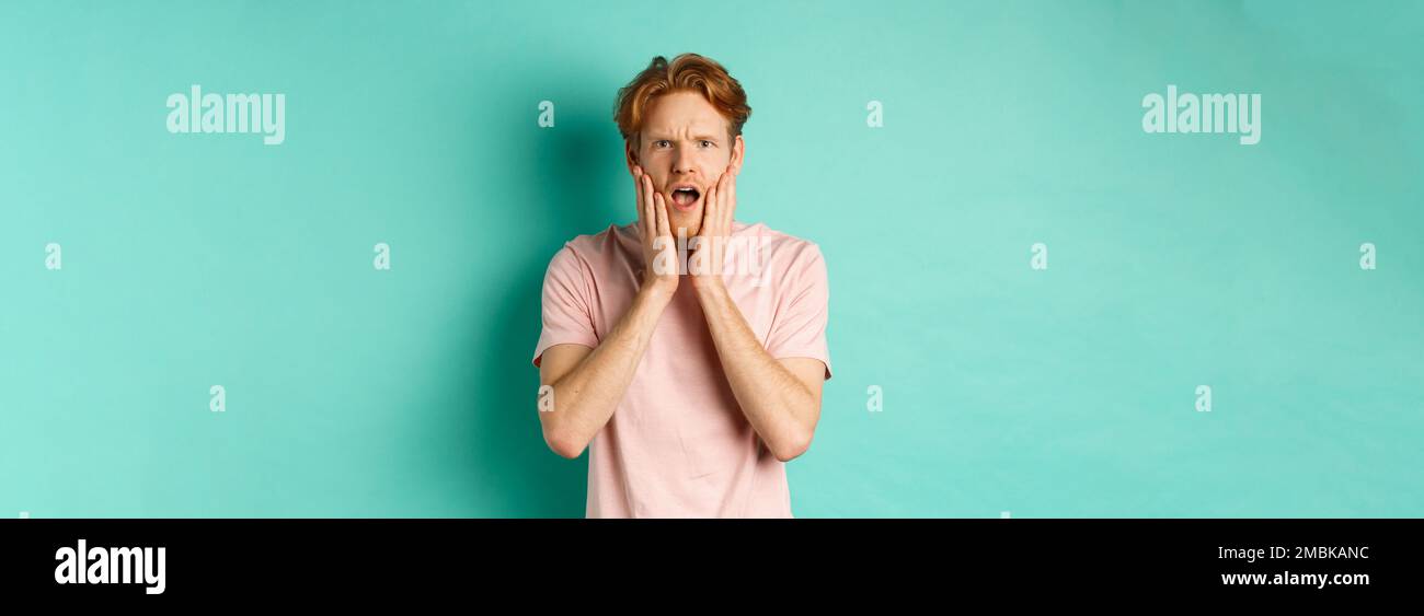Shocked and concerned young man with red hair, staring at camera ...