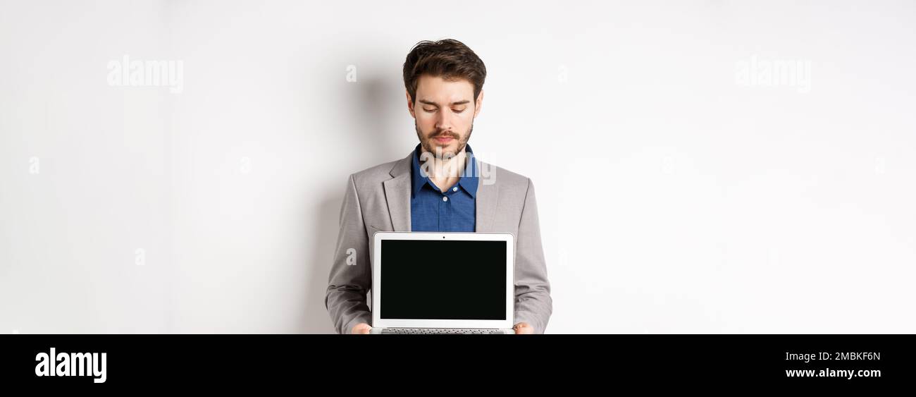 Handsome caucasian businessman in suit showing empty laptop screen ...