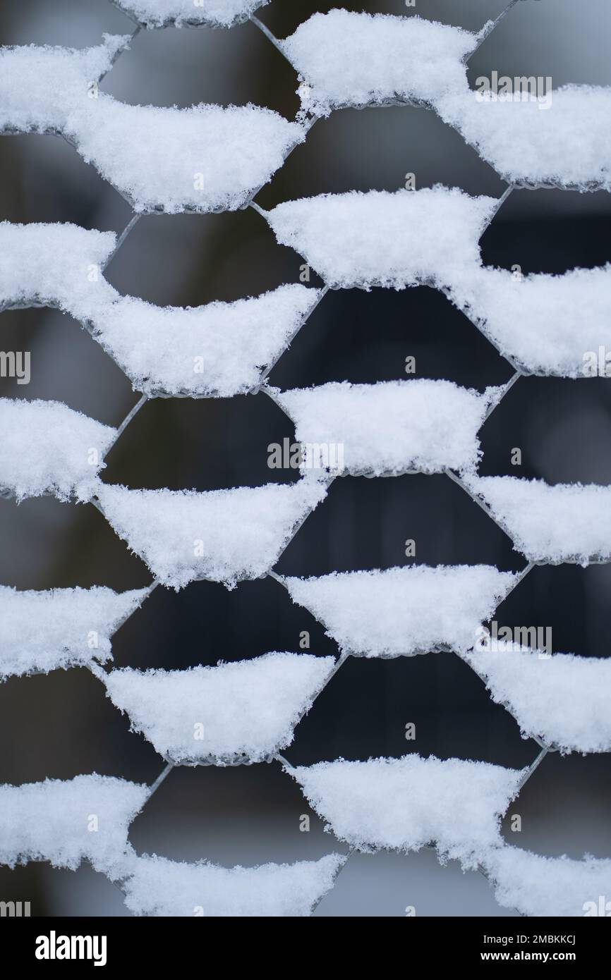 Street fence of thin mesh hawser with snowflakes accumulated in cells ...