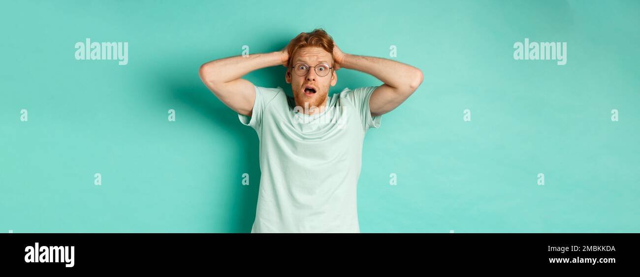 Young redhead man with beard, wearing glasses and t-shirt, holding ...