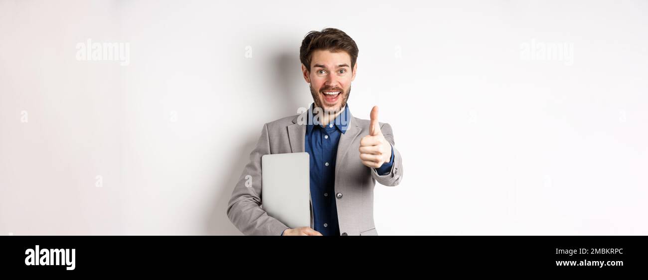 Good job. Happy smiling business man in suit holding laptop, showing ...
