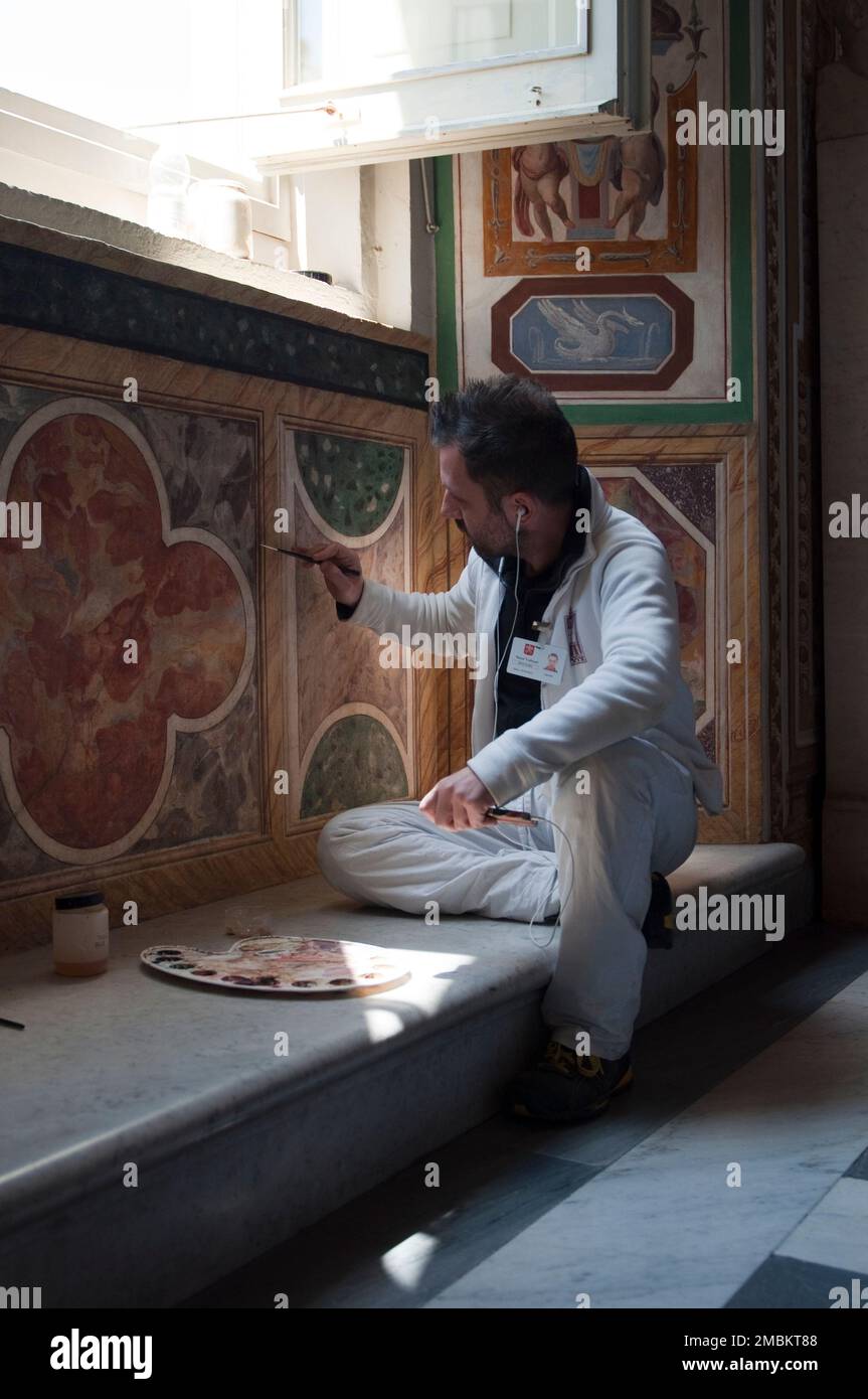A conservator works to restore artwork in the halls of the Vatican ...