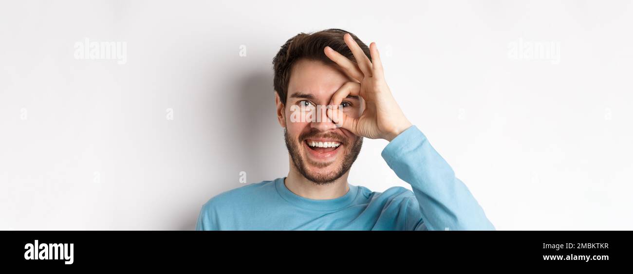 Excited smiling man looking through okay sign with happy face, approve ...