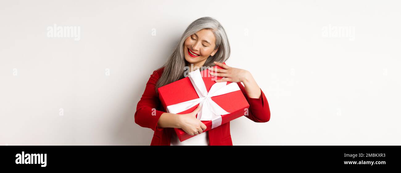 Valentine day concept. Beautiful asian senior woman hugging box with ...