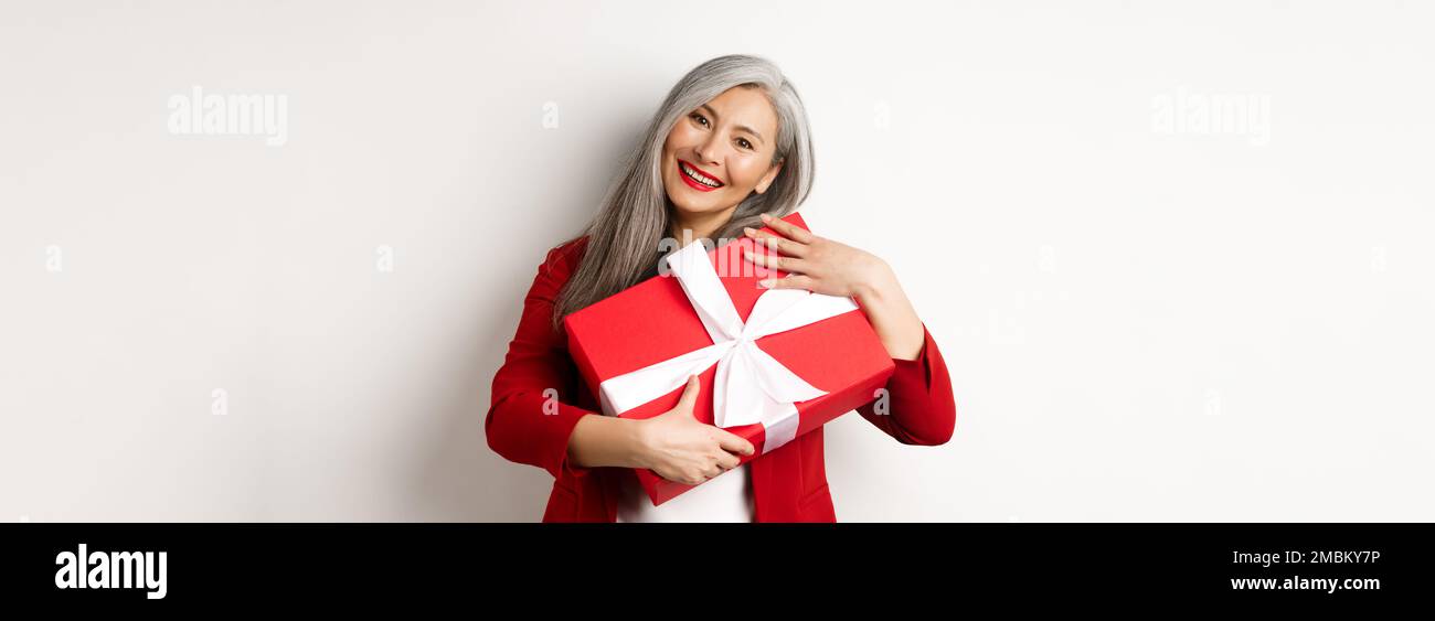 Happy asian grandmother hugging red gift box and smiling grateful ...