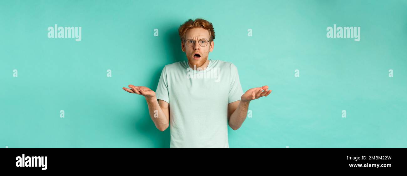 Confused and shocked guy with red messy hair and glasses, shrugging and ...