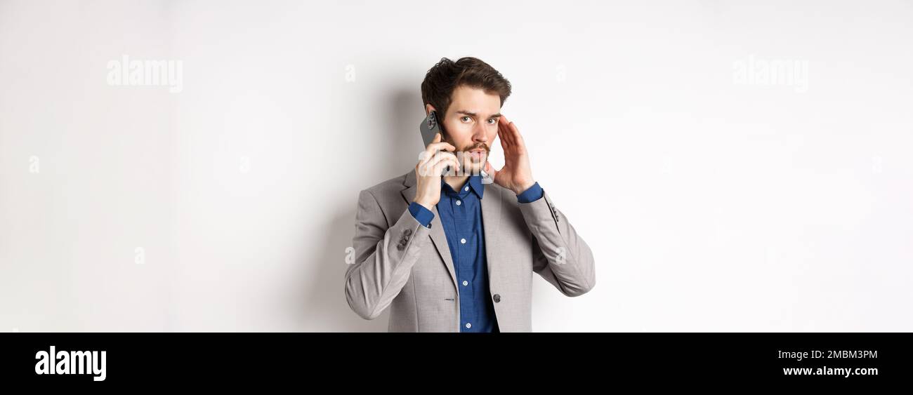 Businessman talking on phone and covering ear, receive call in loud ...