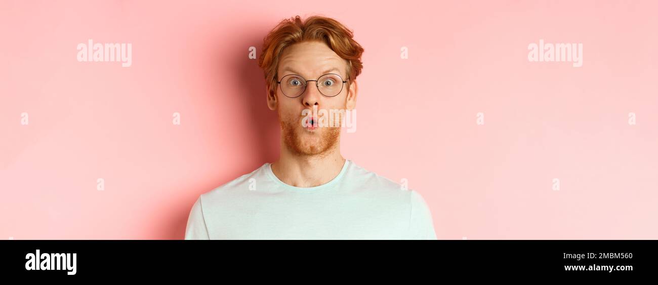 Close up of impressed redhead man in glasses saying wow, raising ...