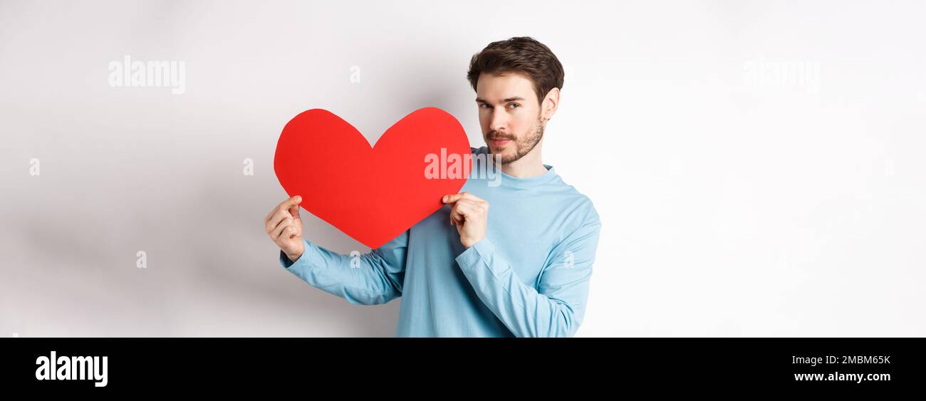 Valentines day. Handsome and romantic man holding big red valentine ...