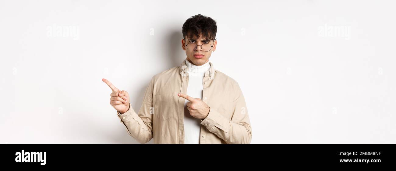 Angry young man frowning and pointing at upper right corner banner ...