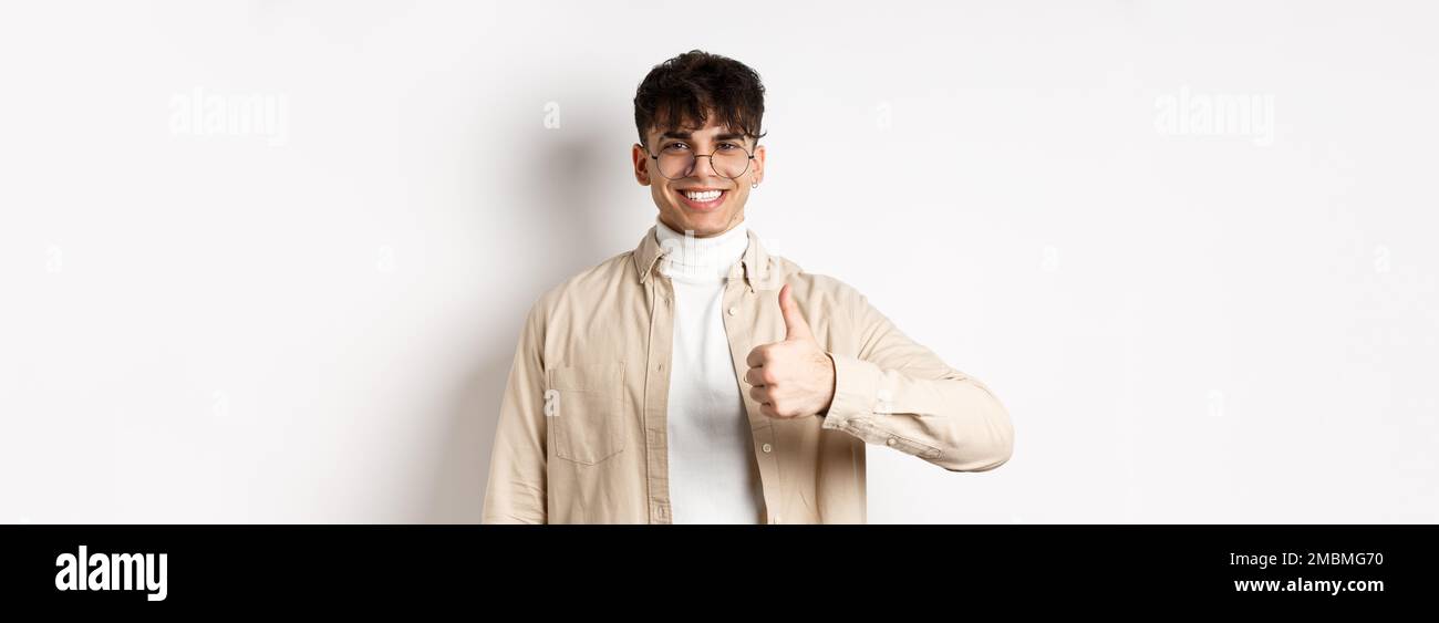 Positive smiling man showing thumbs up and looking satisfied ...