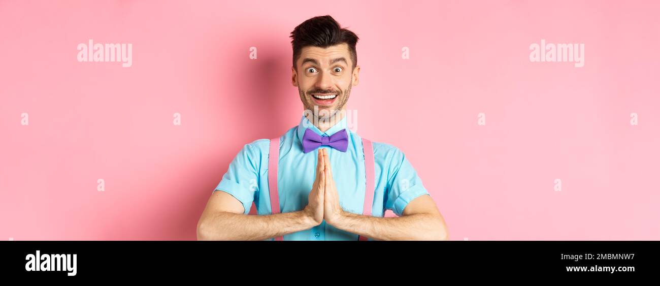Image of smiling young man asking please, looking grateful at camera ...