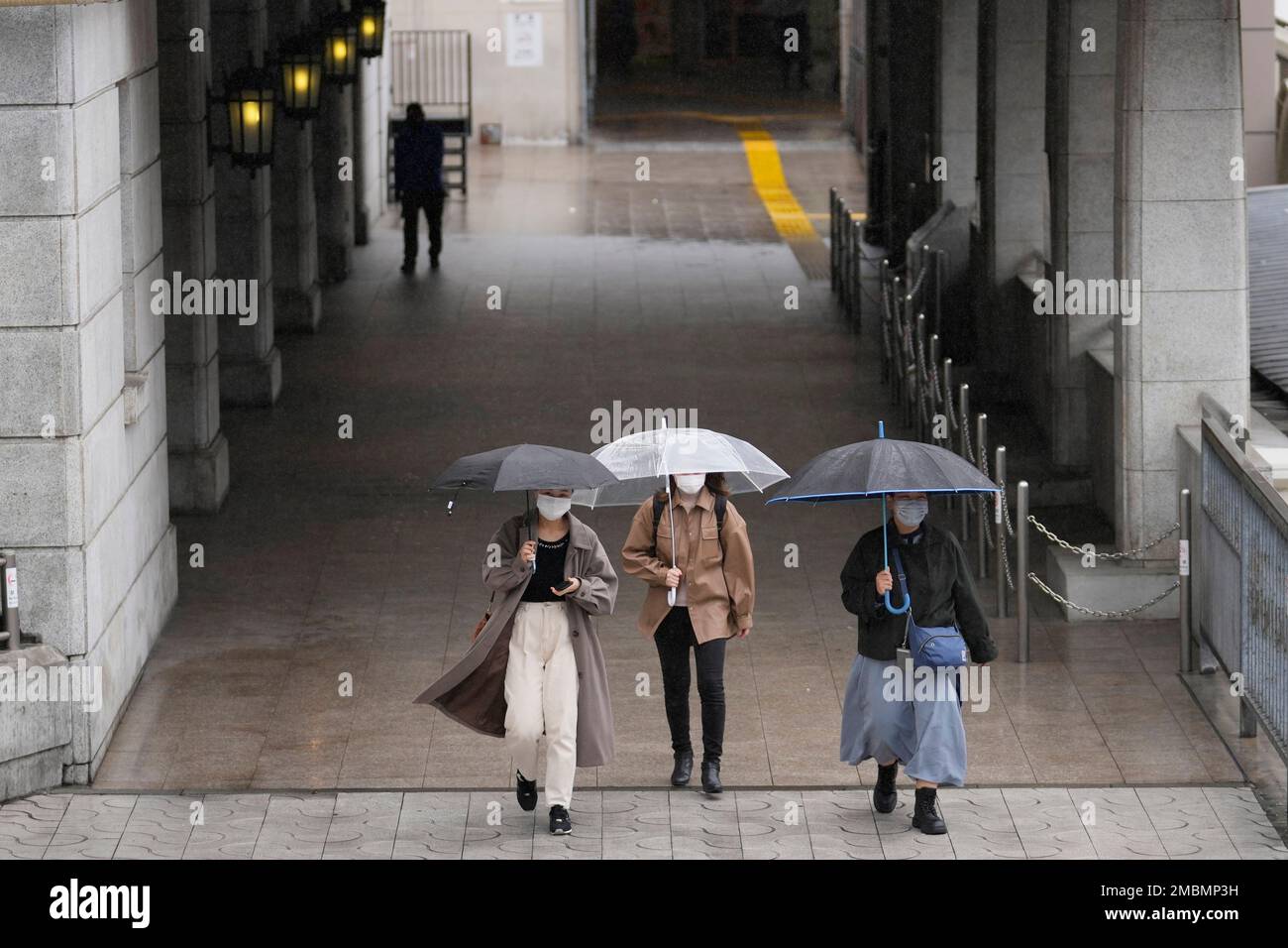 Women wearing face masks walk by a train station in Tokyo, Friday ...