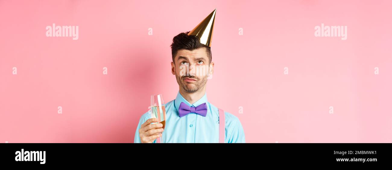 Holidays and celebration concept. Grumpy guy wearing birthday party hat ...