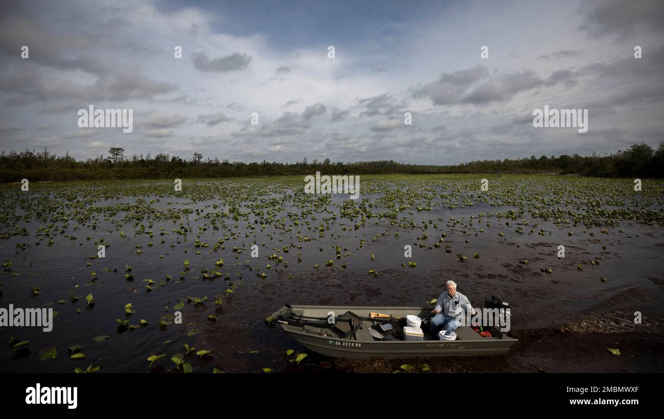 A fisherman motors across an area named double lakes in the Okefenokee ...