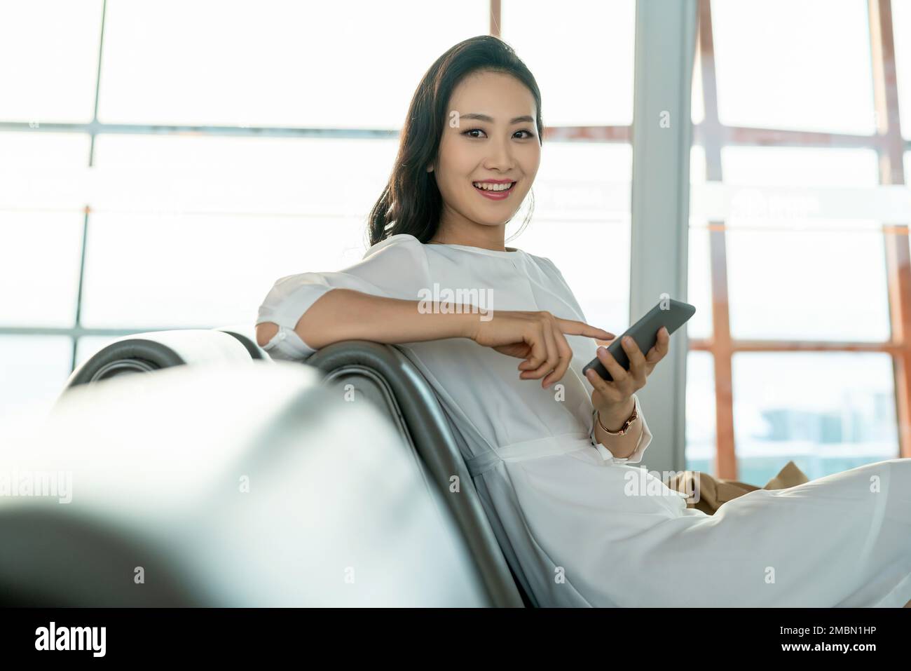 A young woman in the airport lounge with mobile phones Stock Photo - Alamy