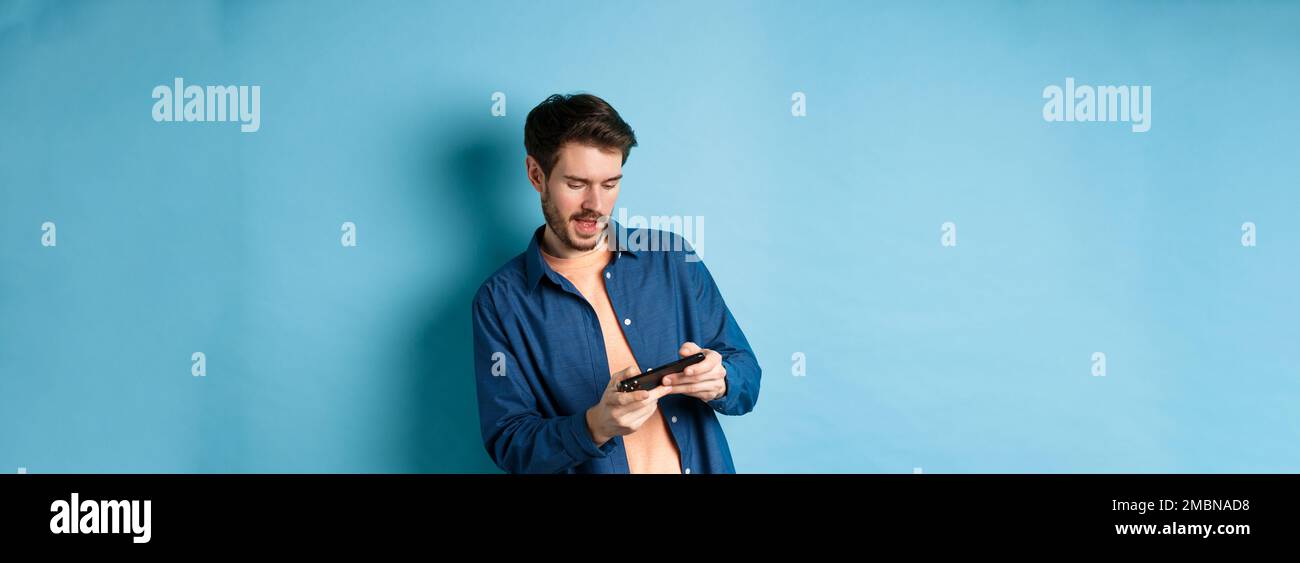 Young guy playing video game on mobile phone, tilt body and holding ...