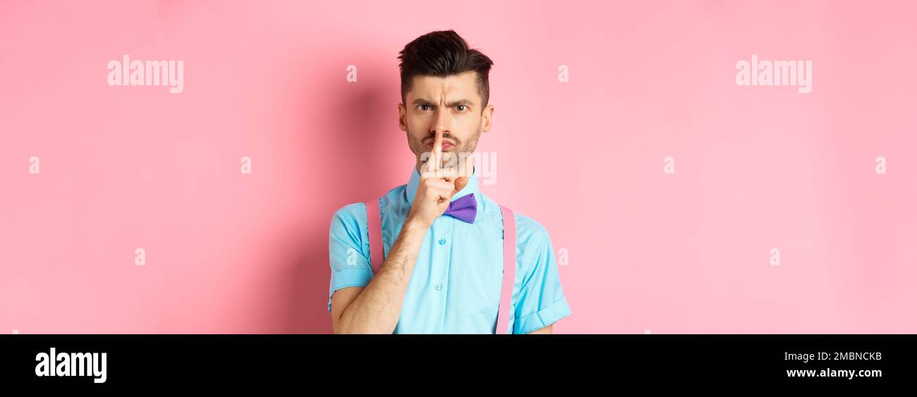 Angry and grumpy man in funny bow-tie shushing at camera, frowning and ...