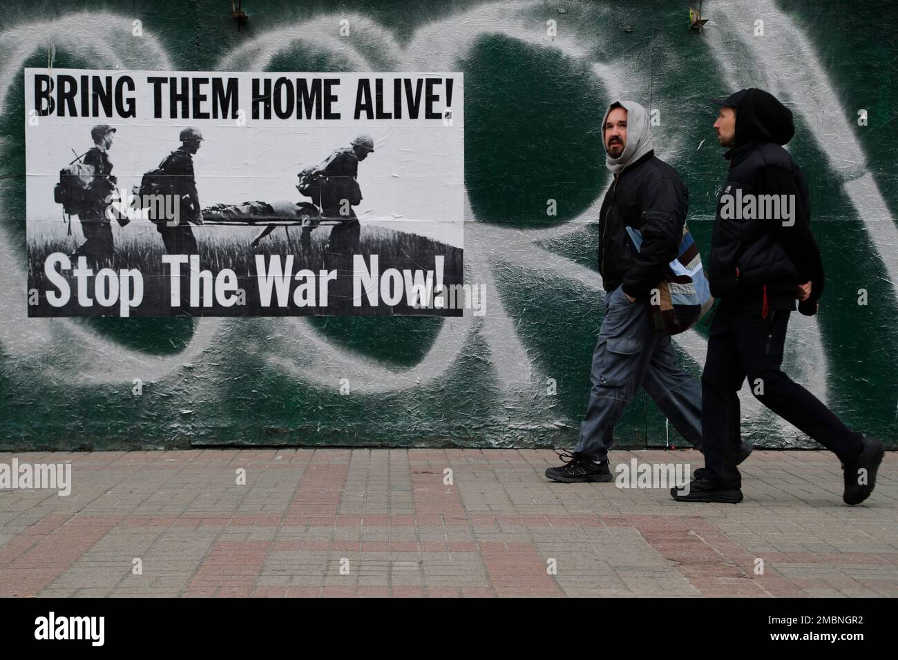 Pedestrians walk past a poster pasted along a street in the center of ...