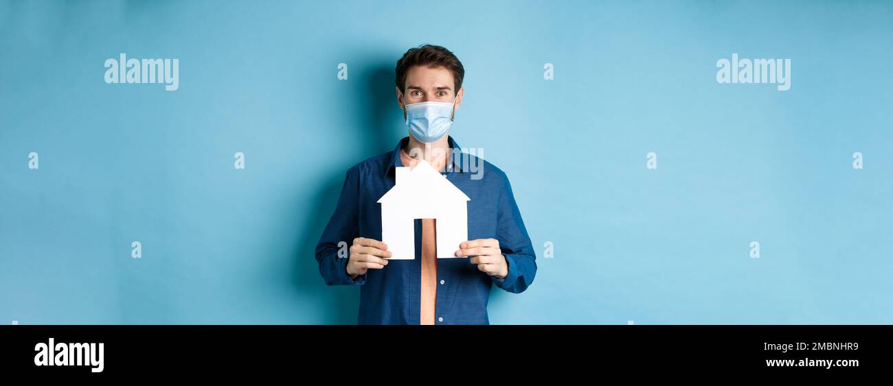 Real estate and quarantine concept. Happy young man in medical mask ...