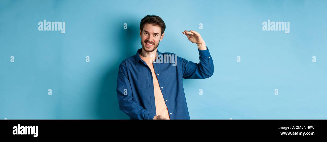 Handsome caucasian guy showing something big, shaping large size object ...