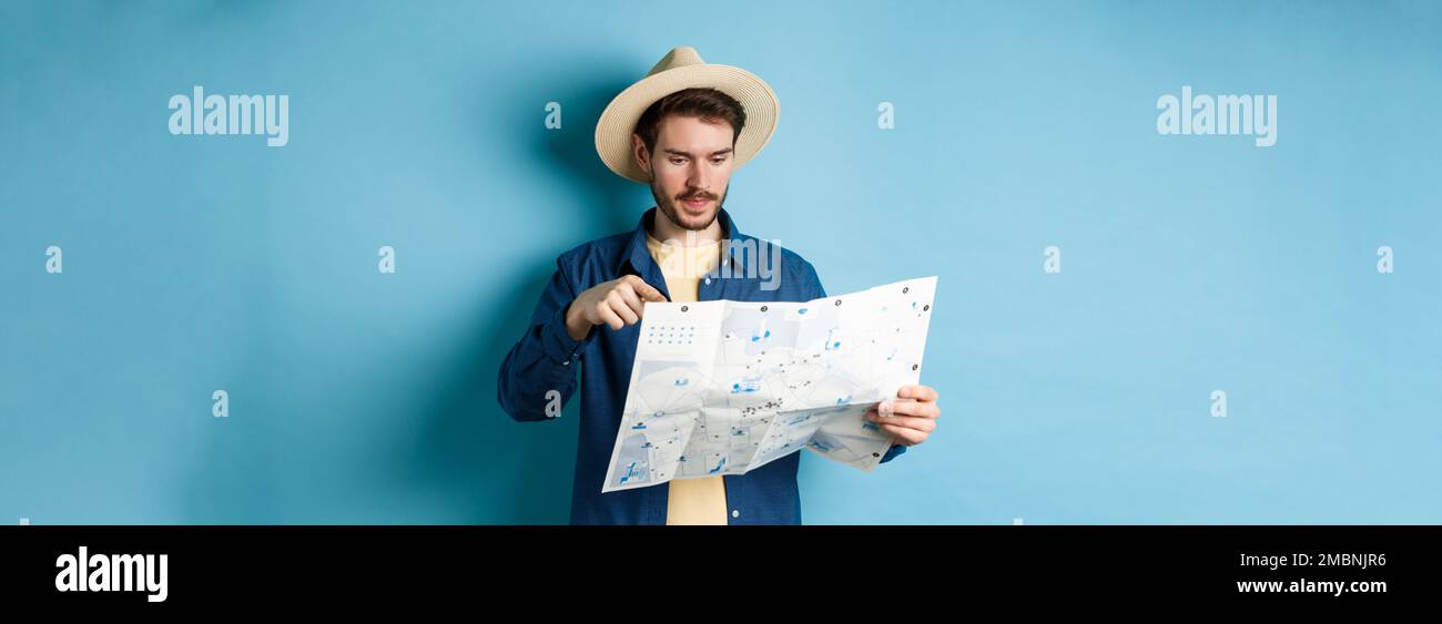 Handsome guy choosing place to go, pointing at sighseeing map on ...