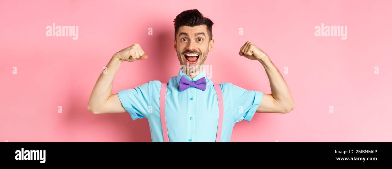 Smiling caucasian man with bow-tie and suspenders, showing muscles and ...