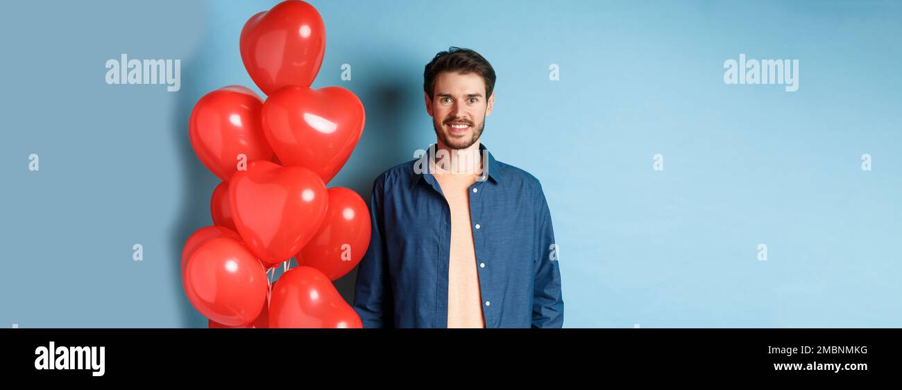 Cute boyfriend looking happy and smiling, standing near Valentines day ...