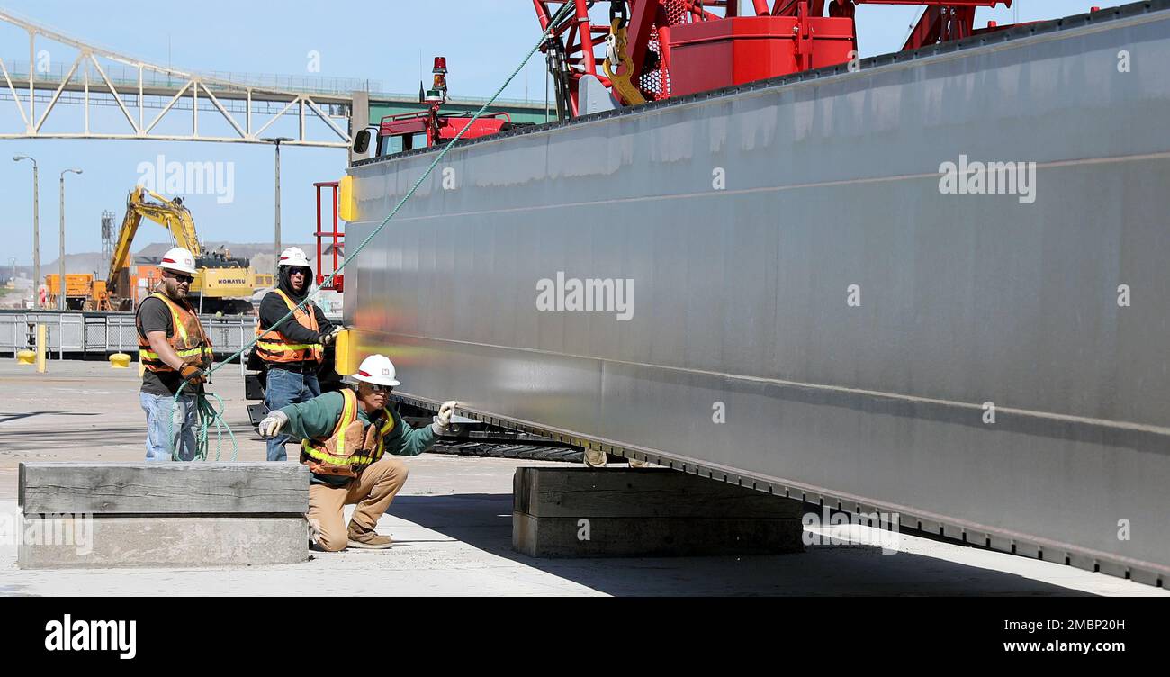 Using hand signals, Jim Young, kneeling, directs the crane operator to ...