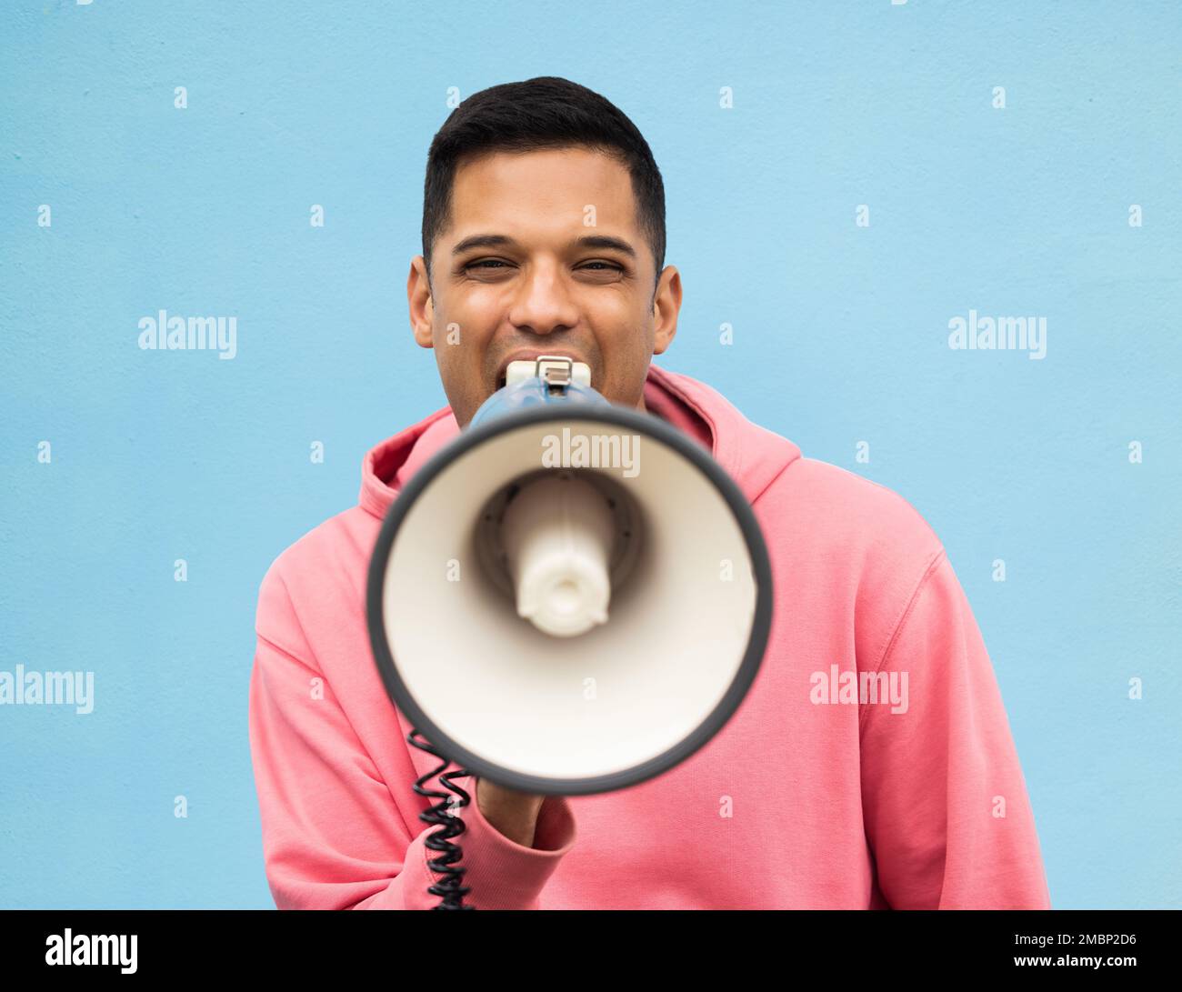 Portrait, protest and megaphone with a man in studio on a blue ...